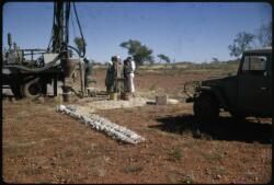 Group of people standing at the rear of a truck mounted drilling rig ...